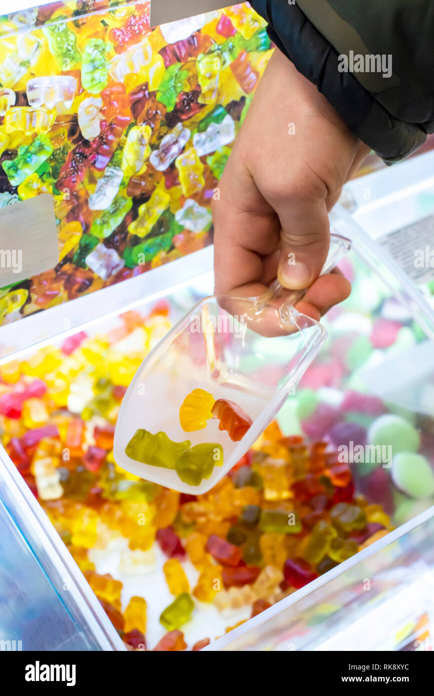 Child hand takes jelly sweets from the showcase on sweets store. Close ...
