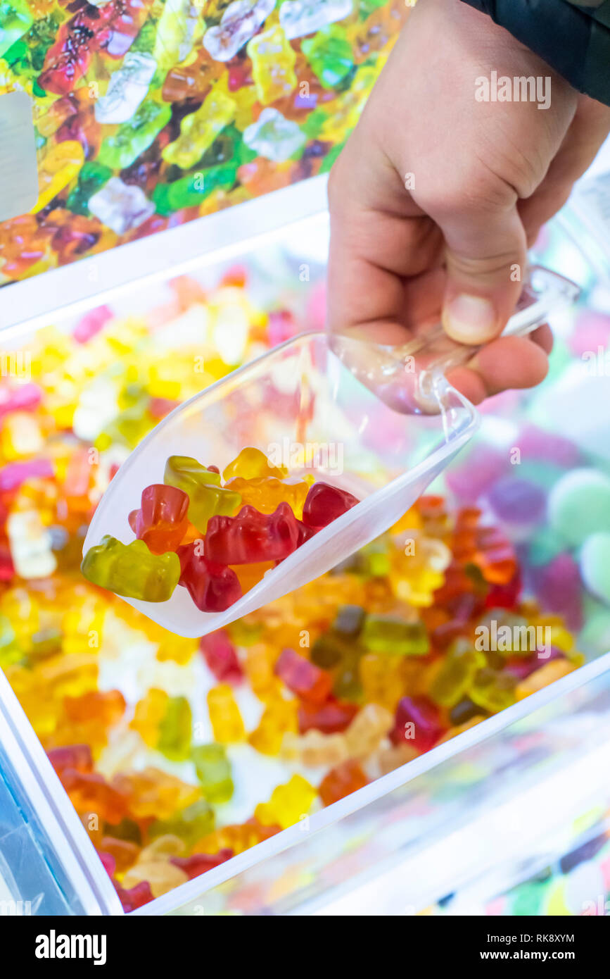 Child hand takes jelly sweets from the showcase on sweets store. Close ...