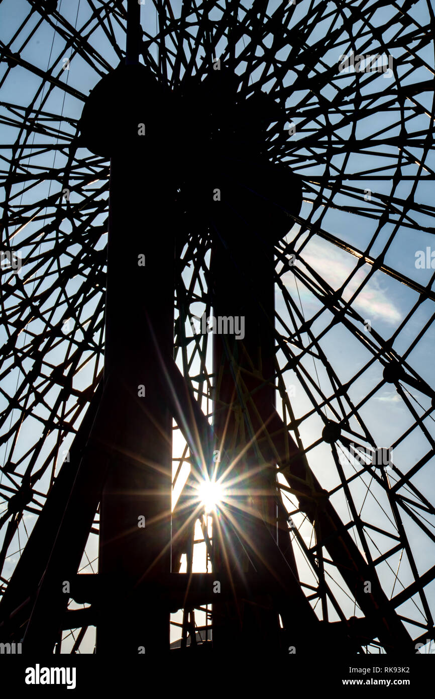 The sun's rays shine through the construction of a carousel. The ...