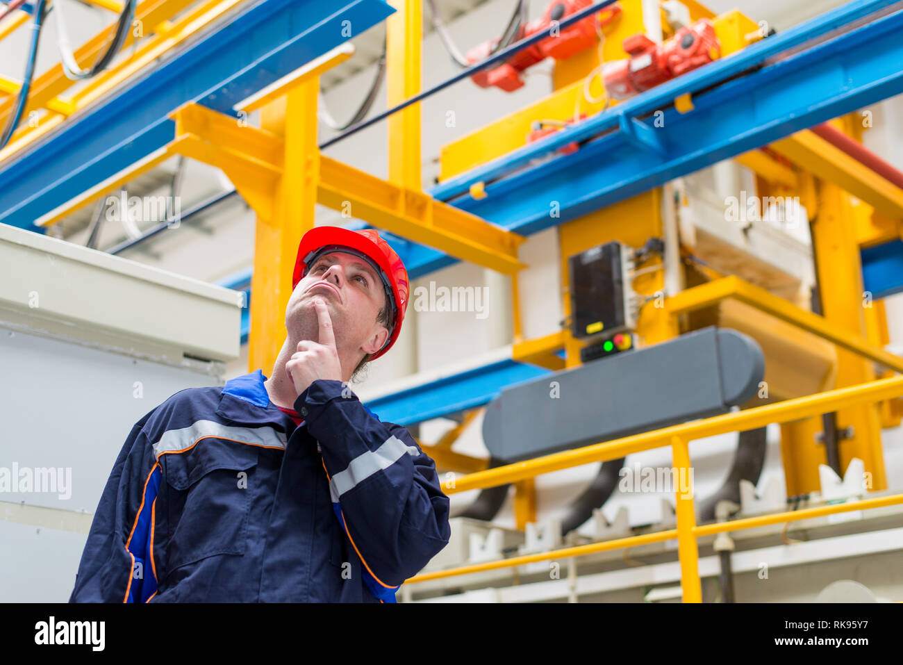 Worker in a factory looking up with machines in the background Stock ...