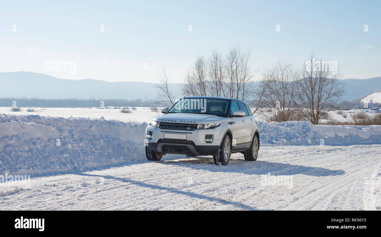 White Range Rover Evoque with a black roof on a winter road on the ...