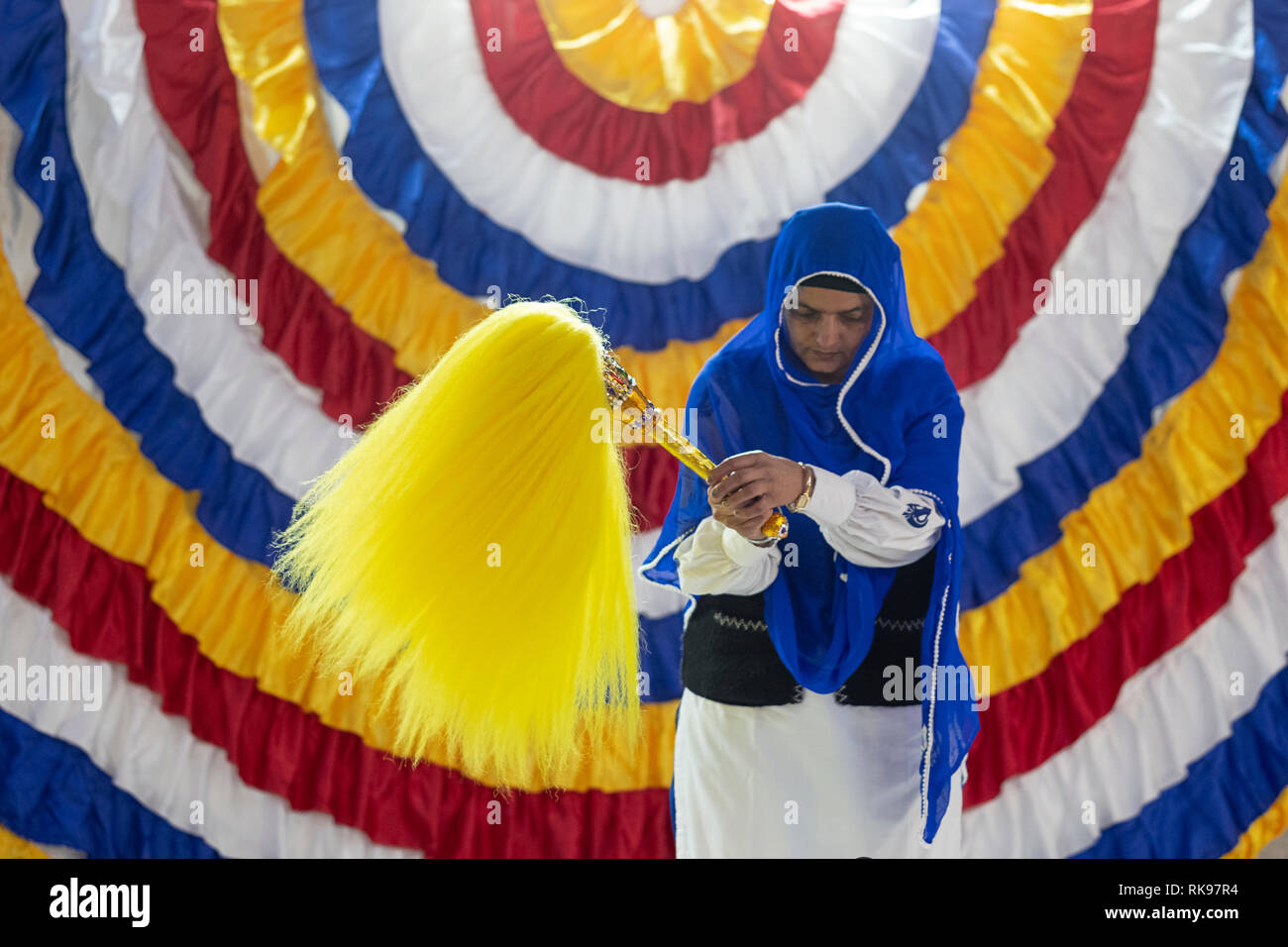 A devout Sikh woman holding a Chaur Sahib which is waving over the holy ...