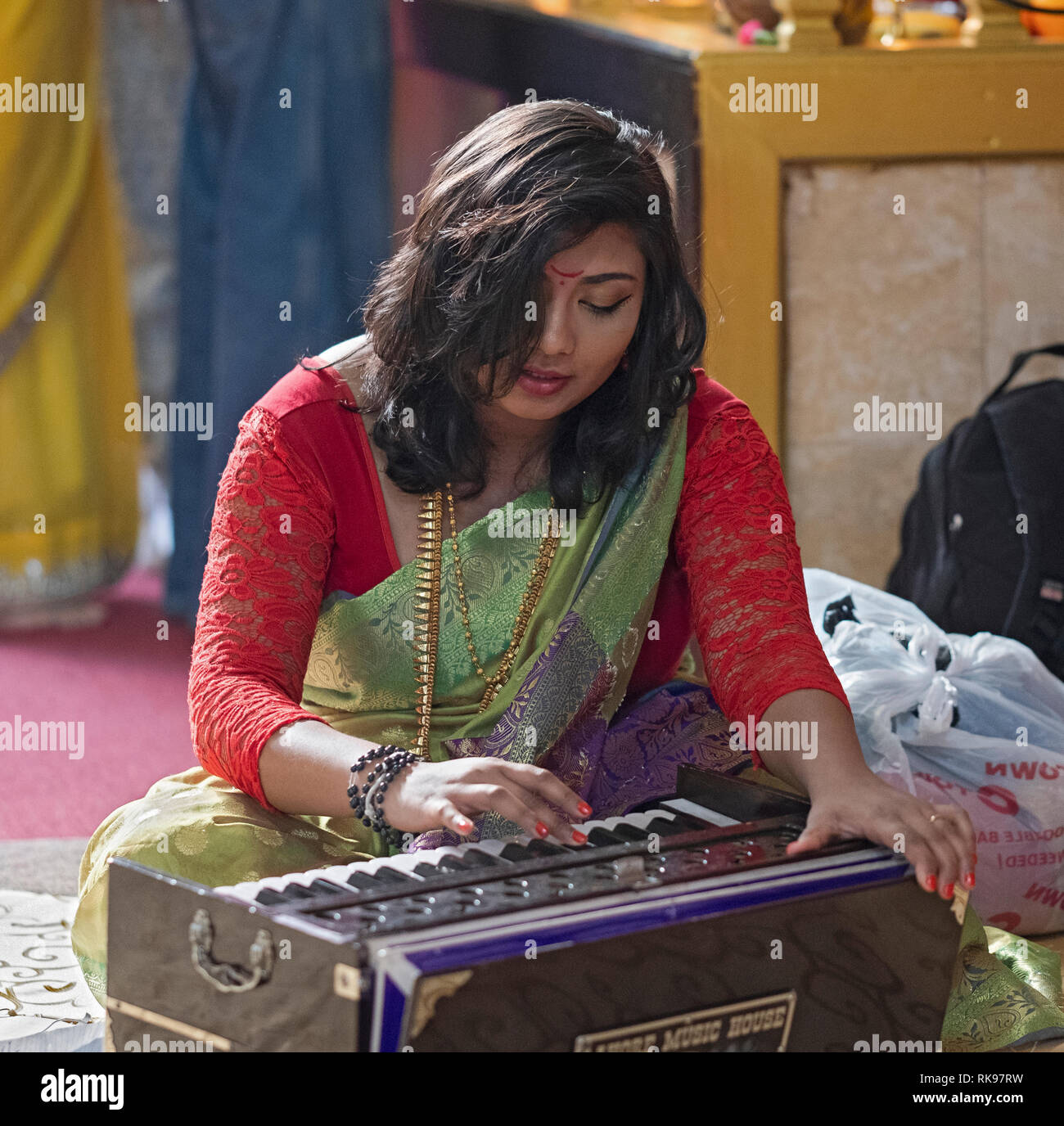 A beautiful Hindu priestess playing the harmonium before morning ...