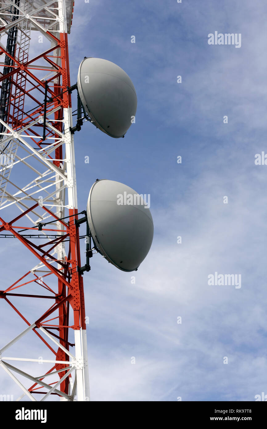 Part of a communications tower with antennas against blue sky with white clouds Stock Photo - Alamy