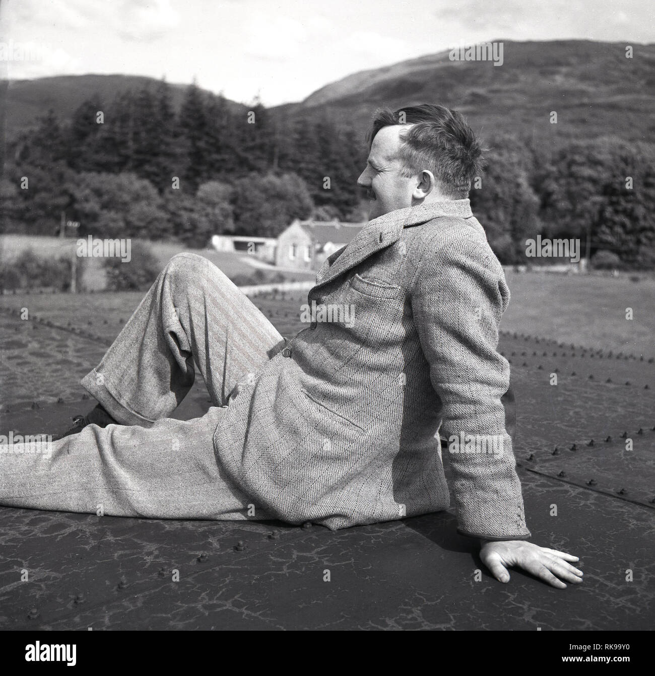 1950s, historical, man in a tweed suit sitting outside on a flat roof ...