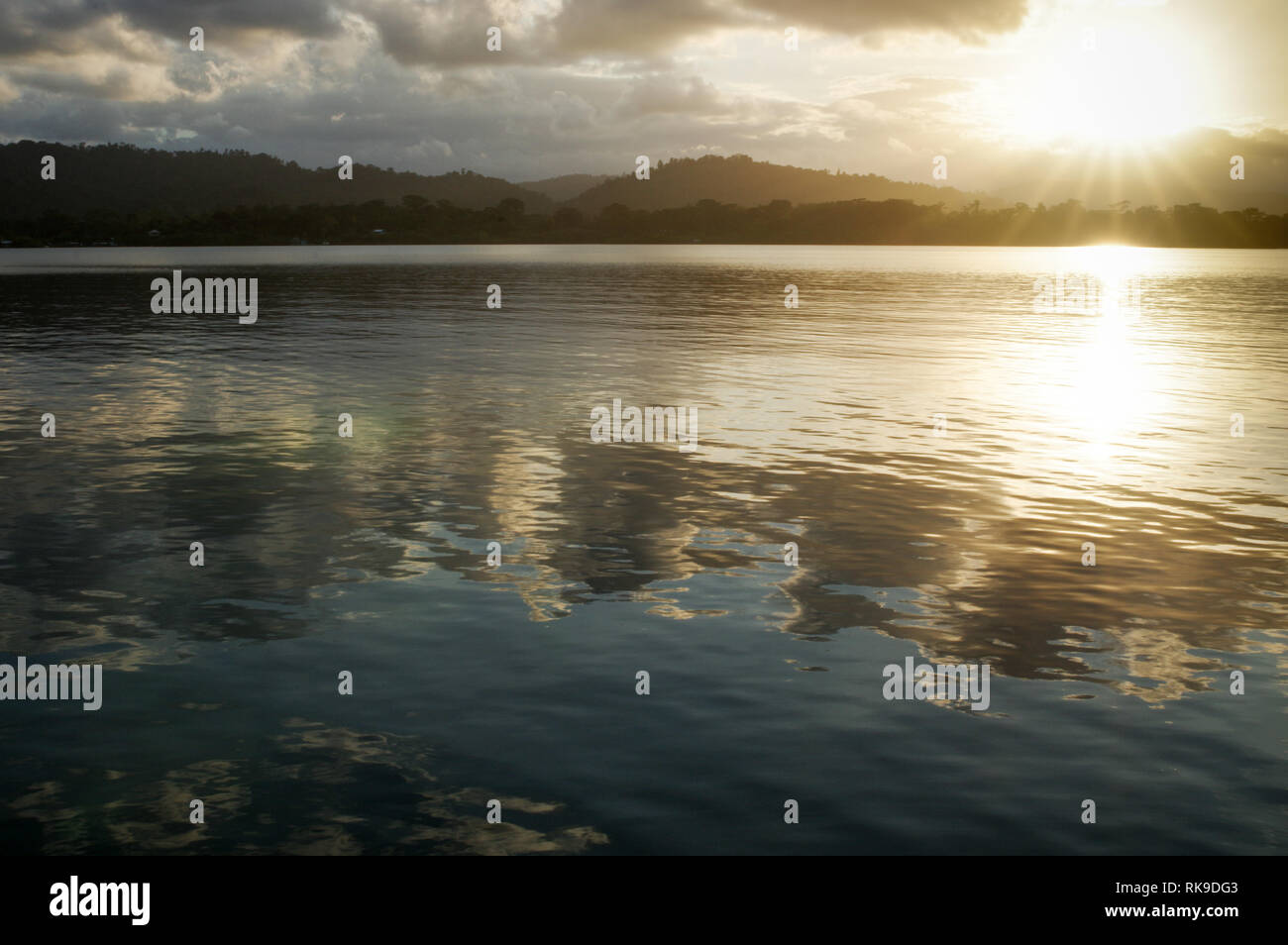 Sun setting behind Tierra Oscura, seen from San Cristobal Island in the ...