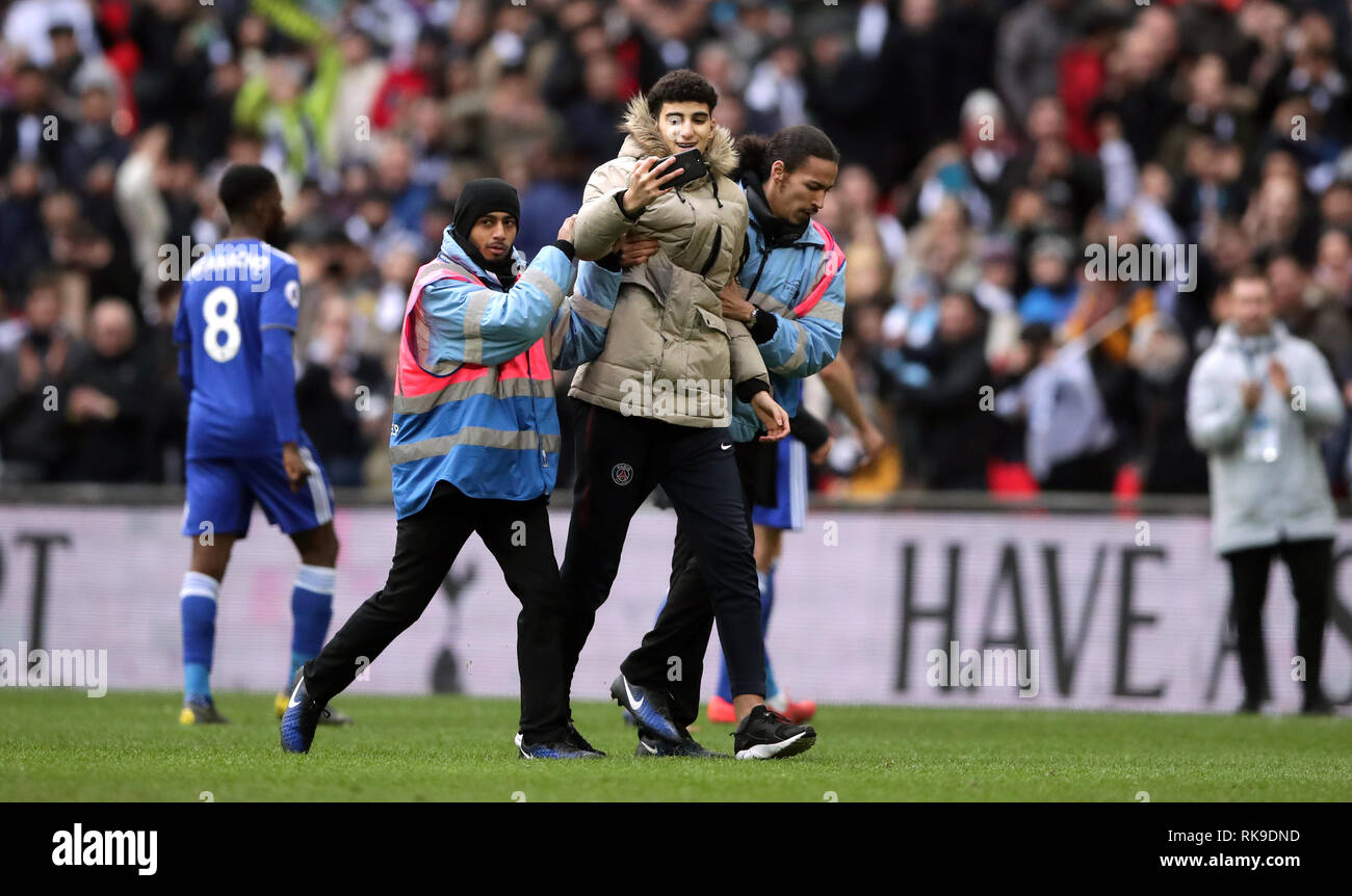 A pitch invader is escorted off by match stewards after the Premier ...