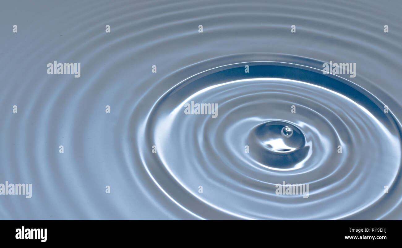 Water droplet creating splash and ripple Stock Photo - Alamy