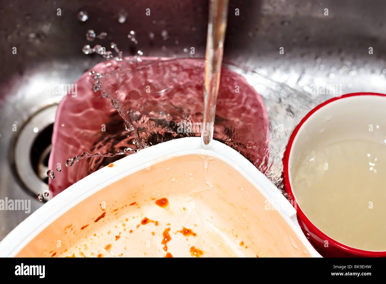 Water running over dirty dishes in metal sink Stock Photo - Alamy
