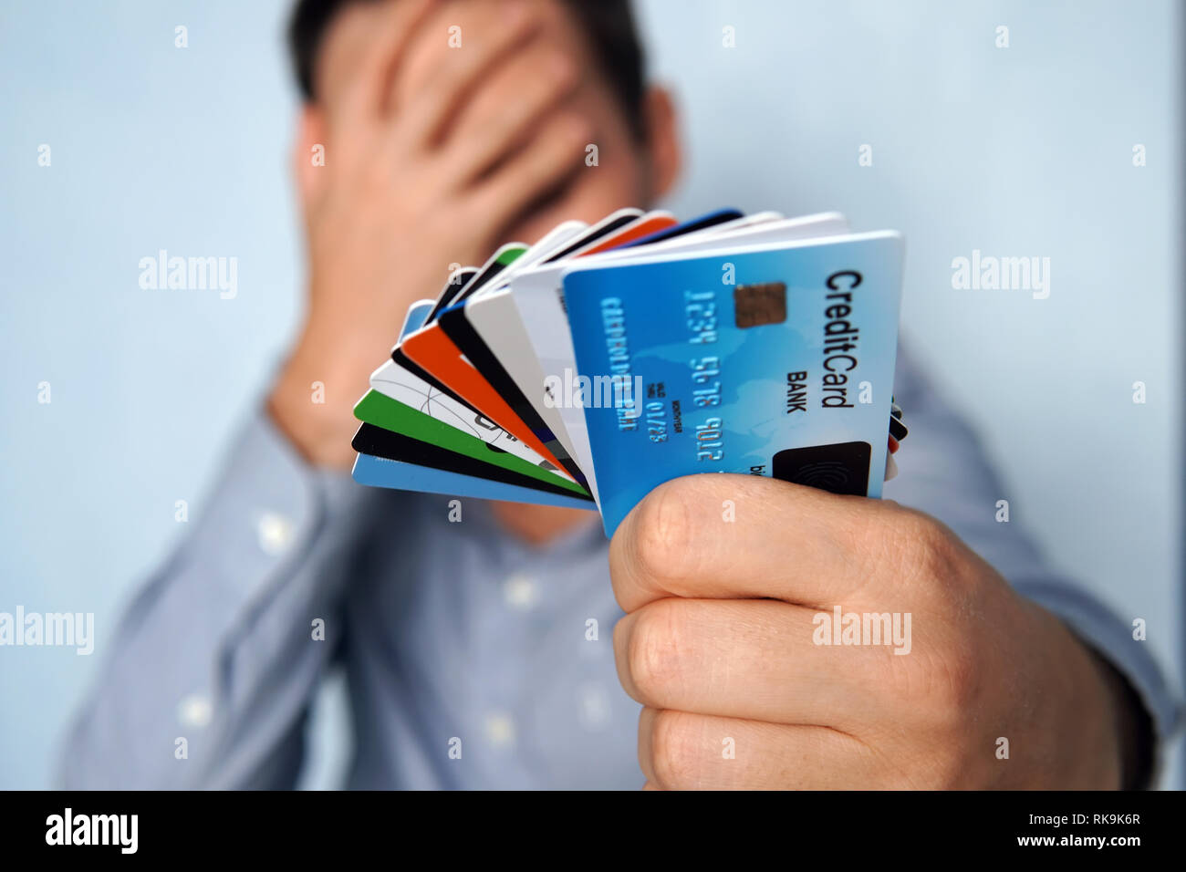 Confused man looking at many credit cards uncertain which one to choose ...