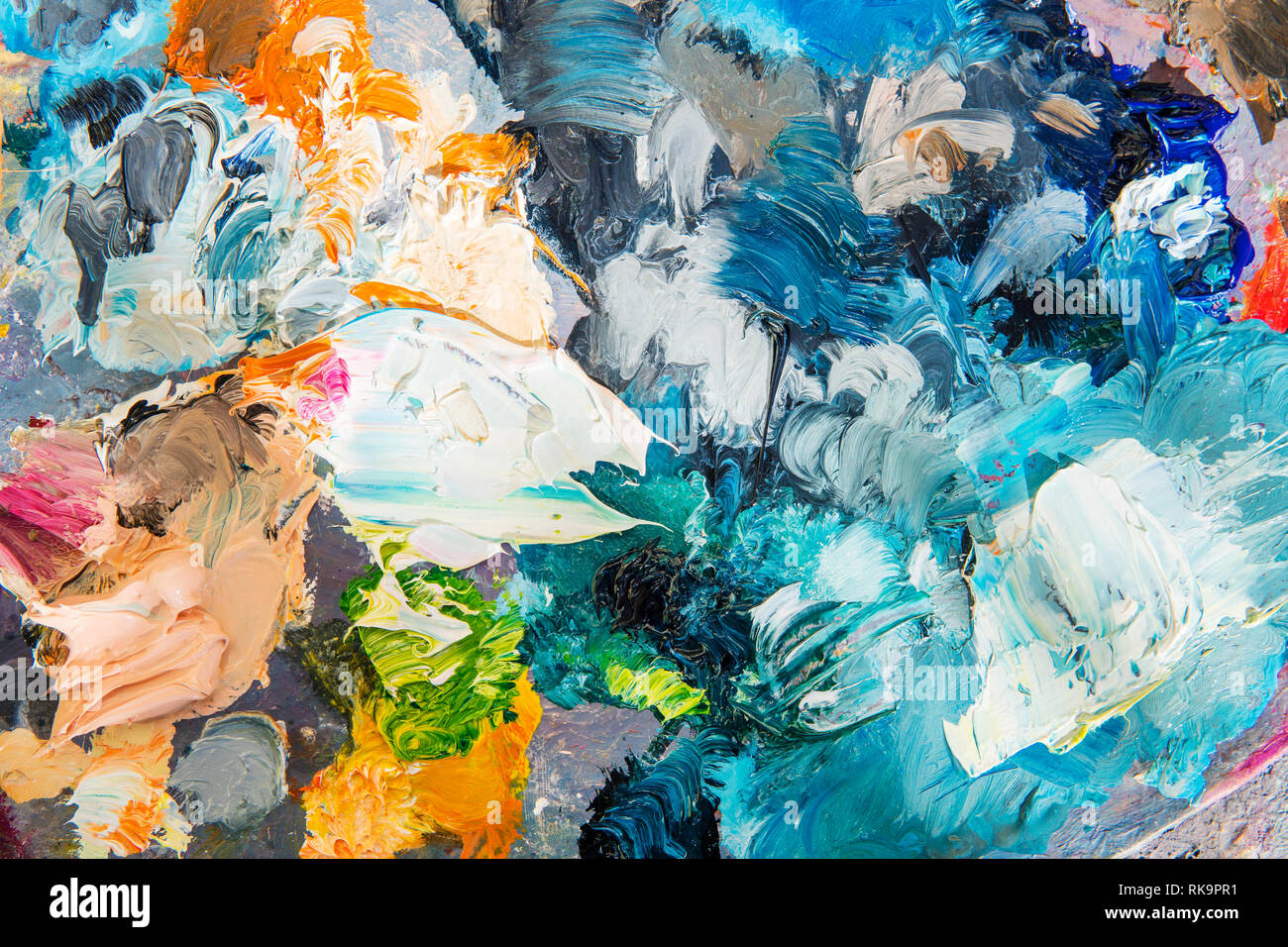 Oils paint spread on painter's palette. Mixing different colors of ...