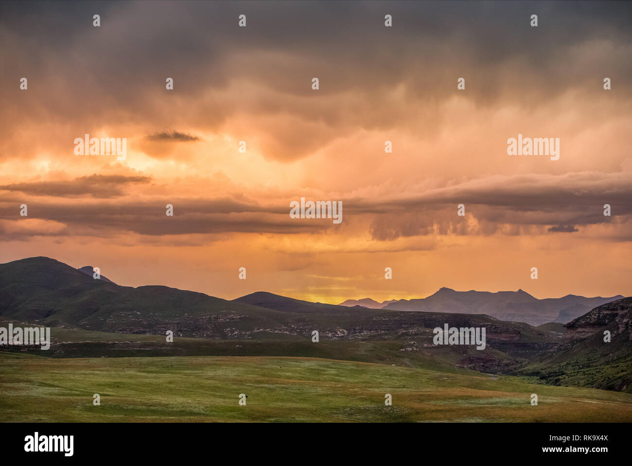 Storm clouds lit in dramatic colours at sunset over the Drakensberg ...