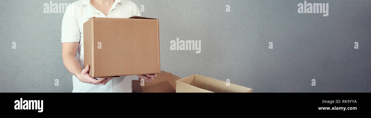 panoramic image of unknown man holding cardboard boxex in his hand ...
