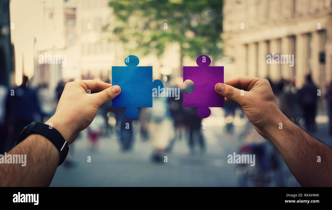 Two hands holding different colored puzzle pieces, unite jigsaw over a ...