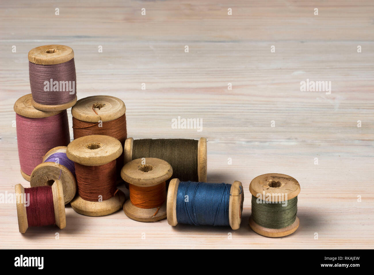 Old spools of thread on a wooden background Stock Photo - Alamy