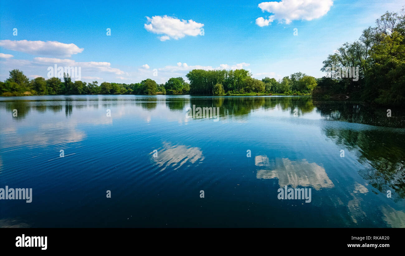 Panorama of a big calm lake reflecting the sky Stock Photo - Alamy