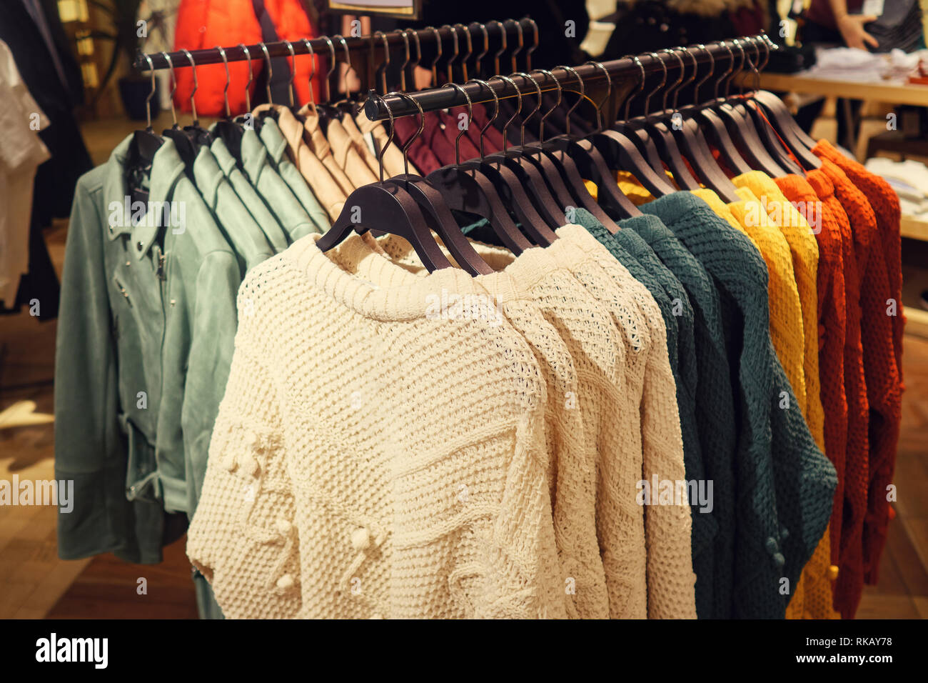 Stylish multicolored sweaters on rack Stock Photo - Alamy
