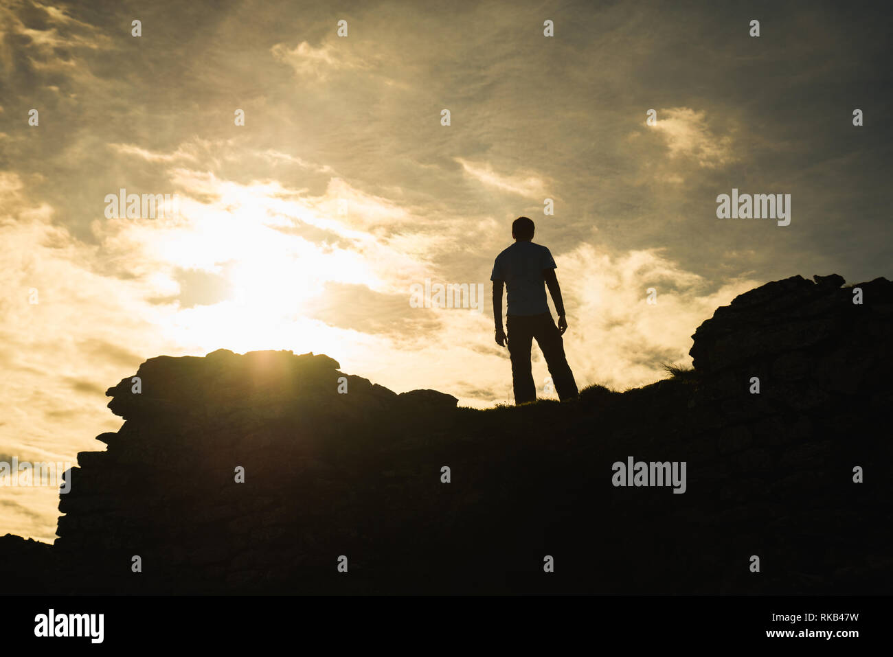 Man silhouette on top of a cliff watching sunset, golden colors Stock ...
