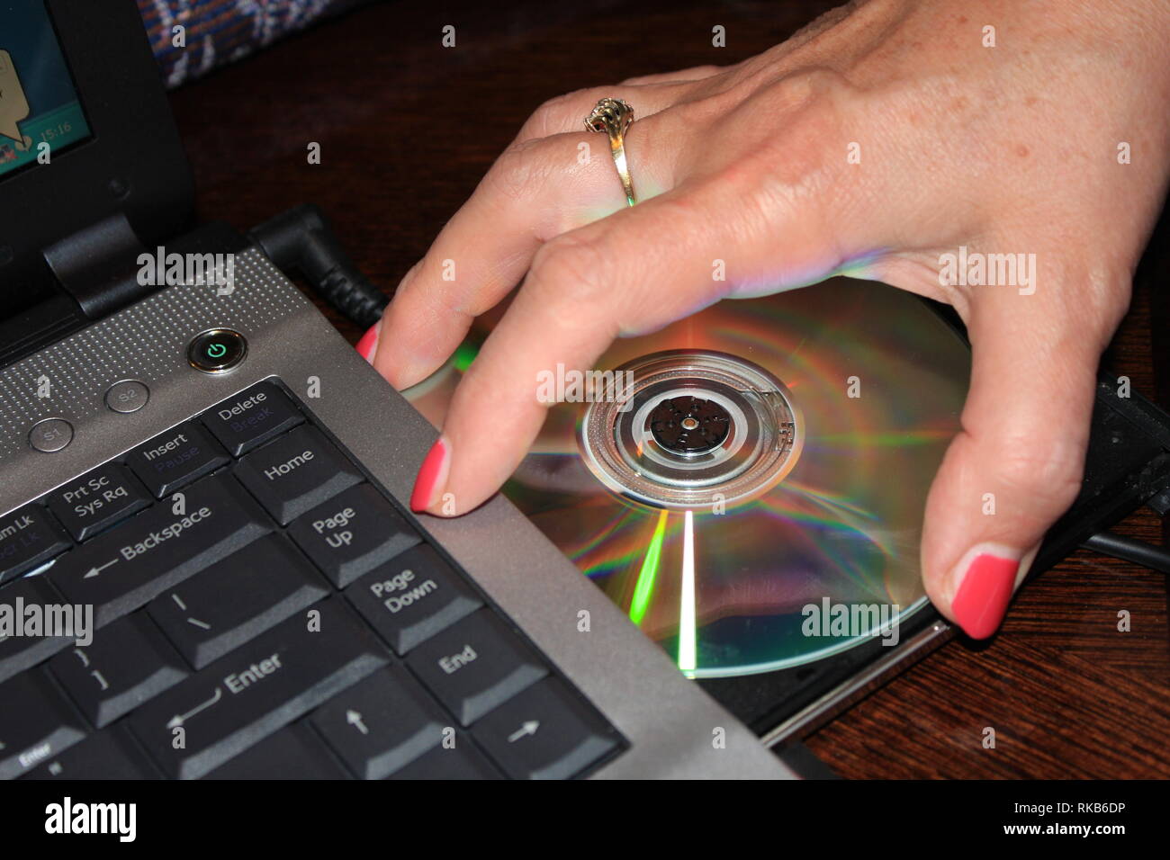 Inserting CD by womans hand Stock Photo - Alamy