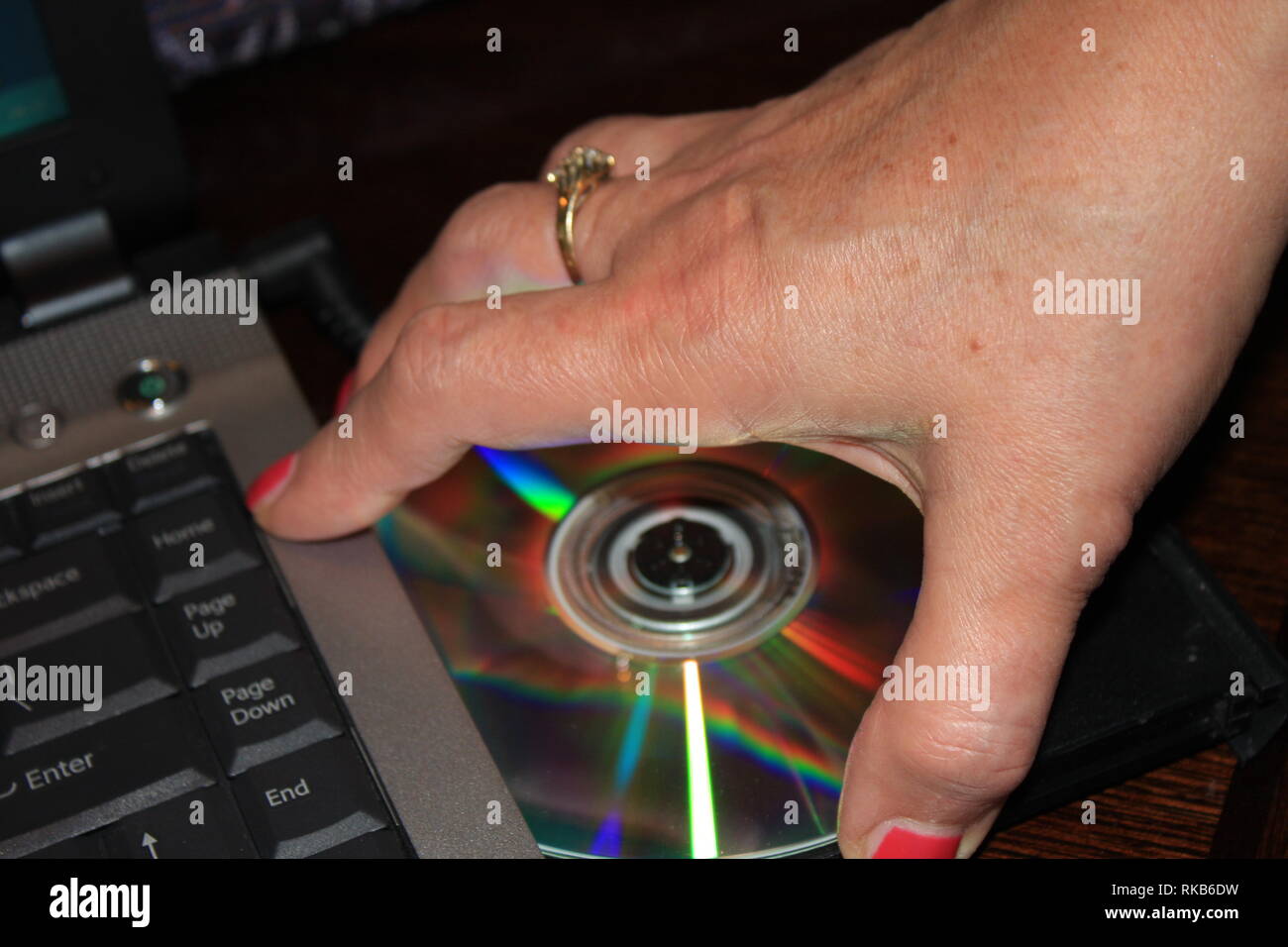 Inserting CD by womans hand Stock Photo - Alamy