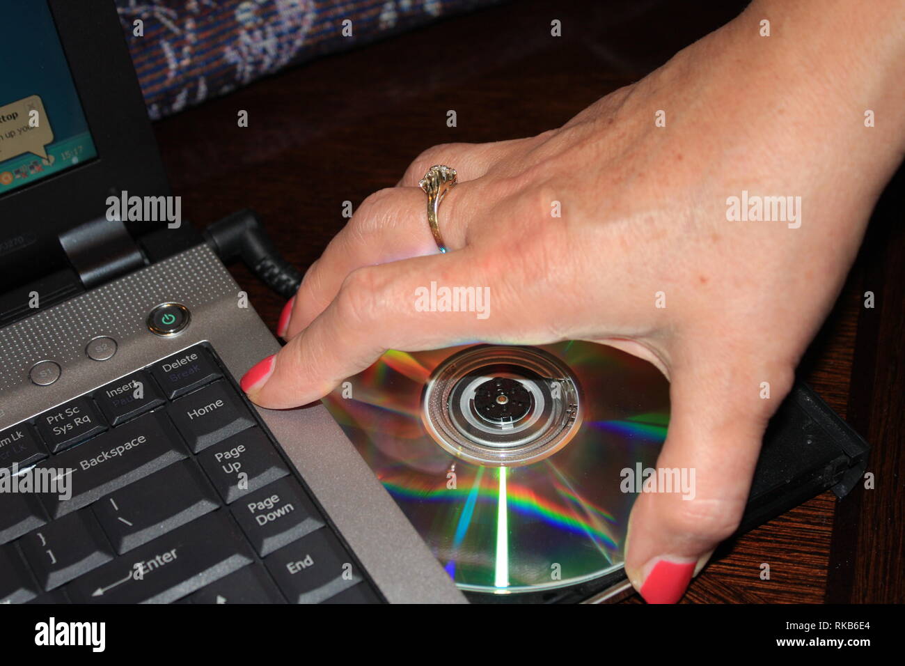 Inserting CD by womans hand Stock Photo - Alamy