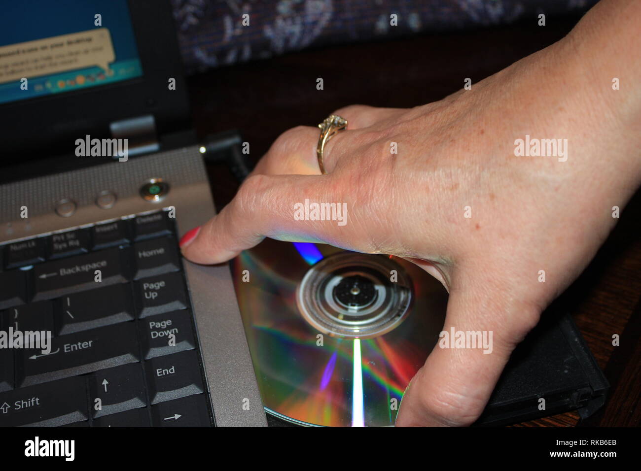 Inserting CD by womans hand Stock Photo - Alamy