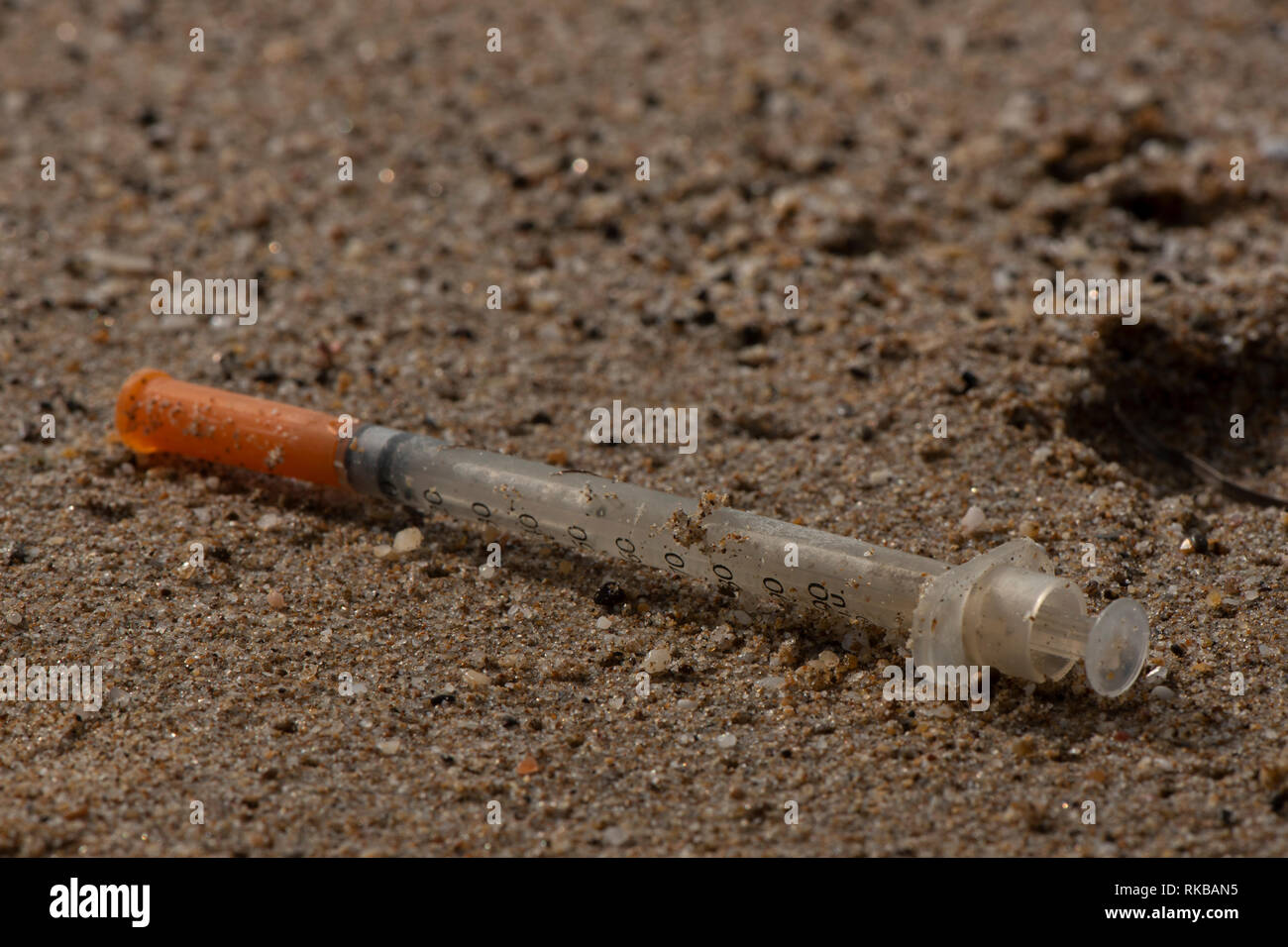 the old drug addict's syringe is lying on the sand. syringe with cap ...