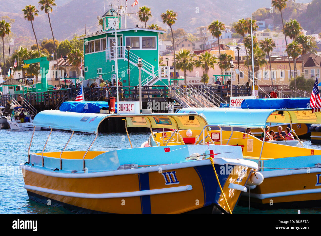 Yellow and blue shore boats sit at anchor along the iconic green pier ...