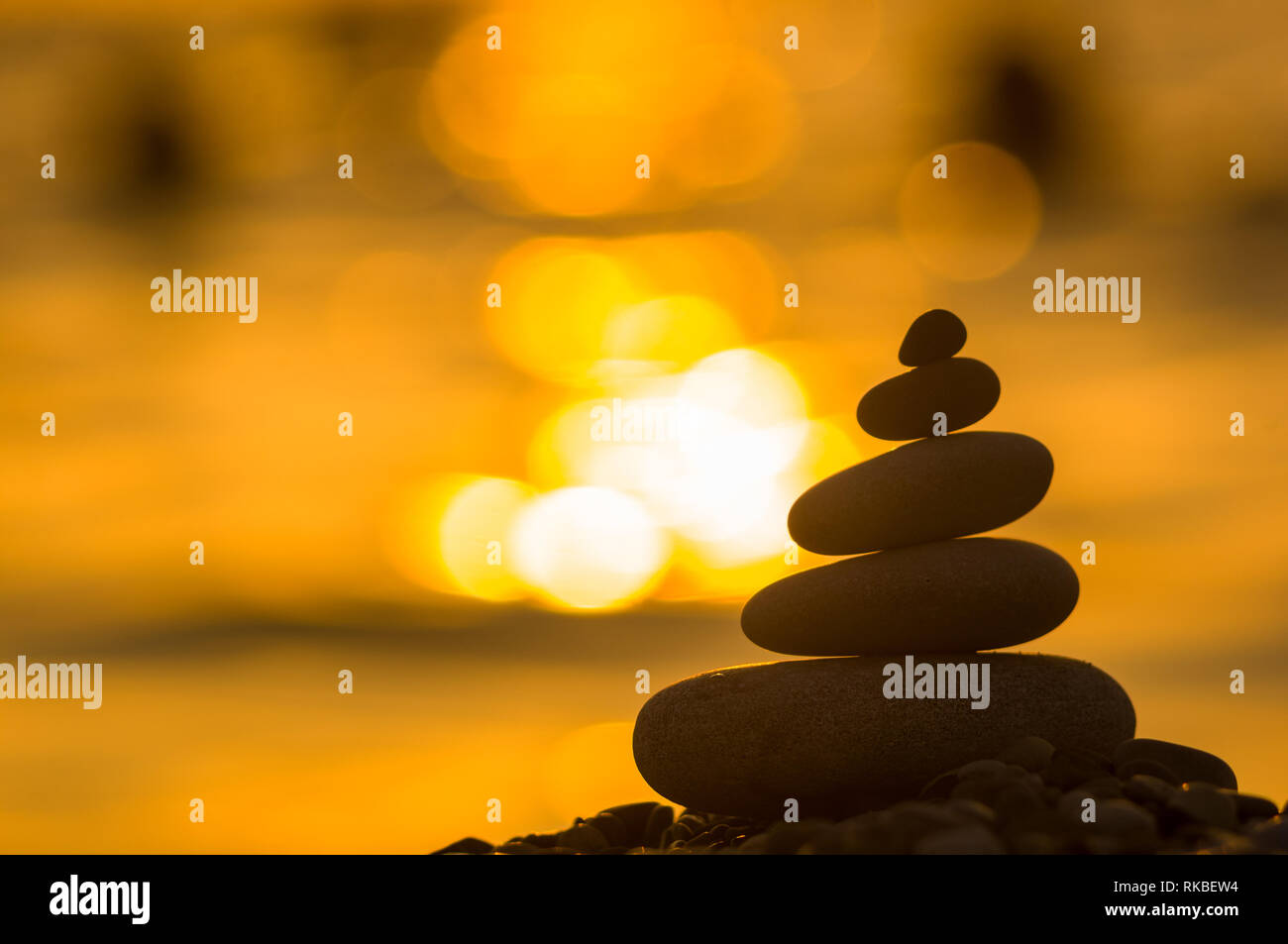 folded pyramid Zen pebble stones on the sea beach at sunset Stock Photo ...