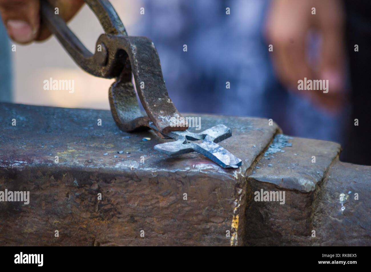blacksmith performs the forging of hot glowing metal on the anvil ...