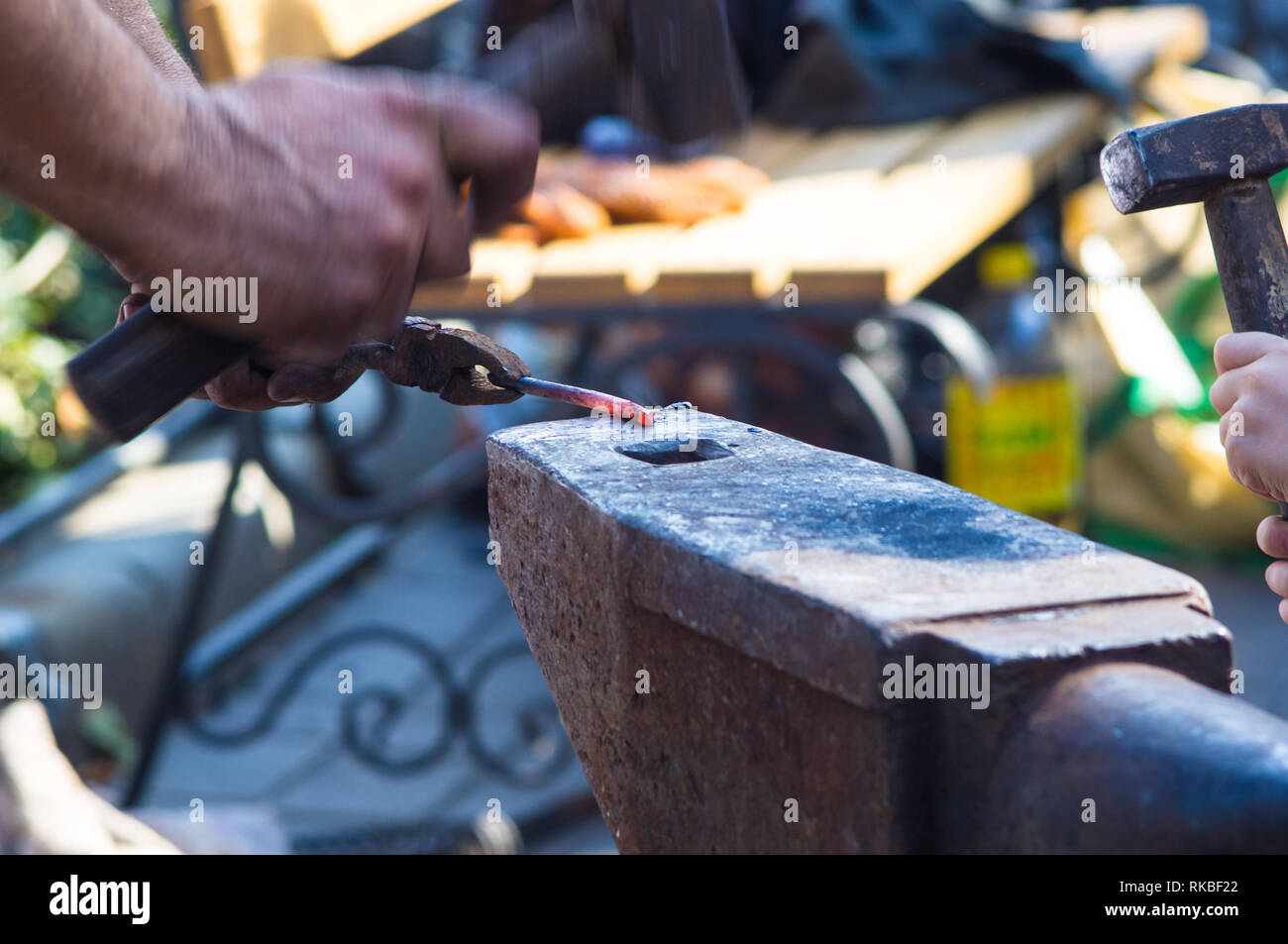 blacksmith performs the forging of hot glowing metal on the anvil ...