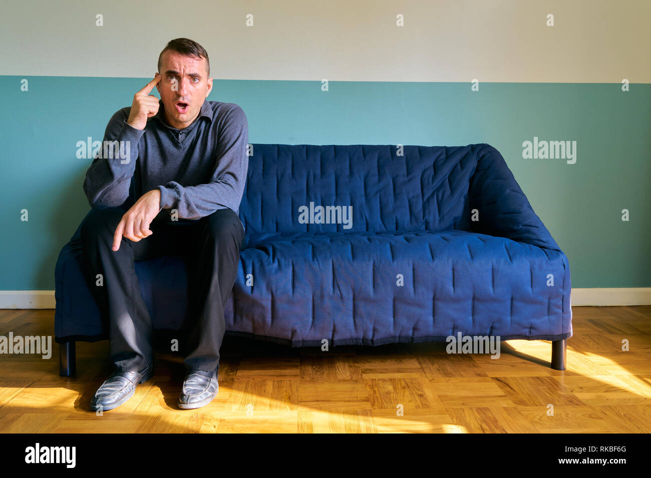 Handsome guy posing - angry and stressed man sitting on the sofa Stock ...