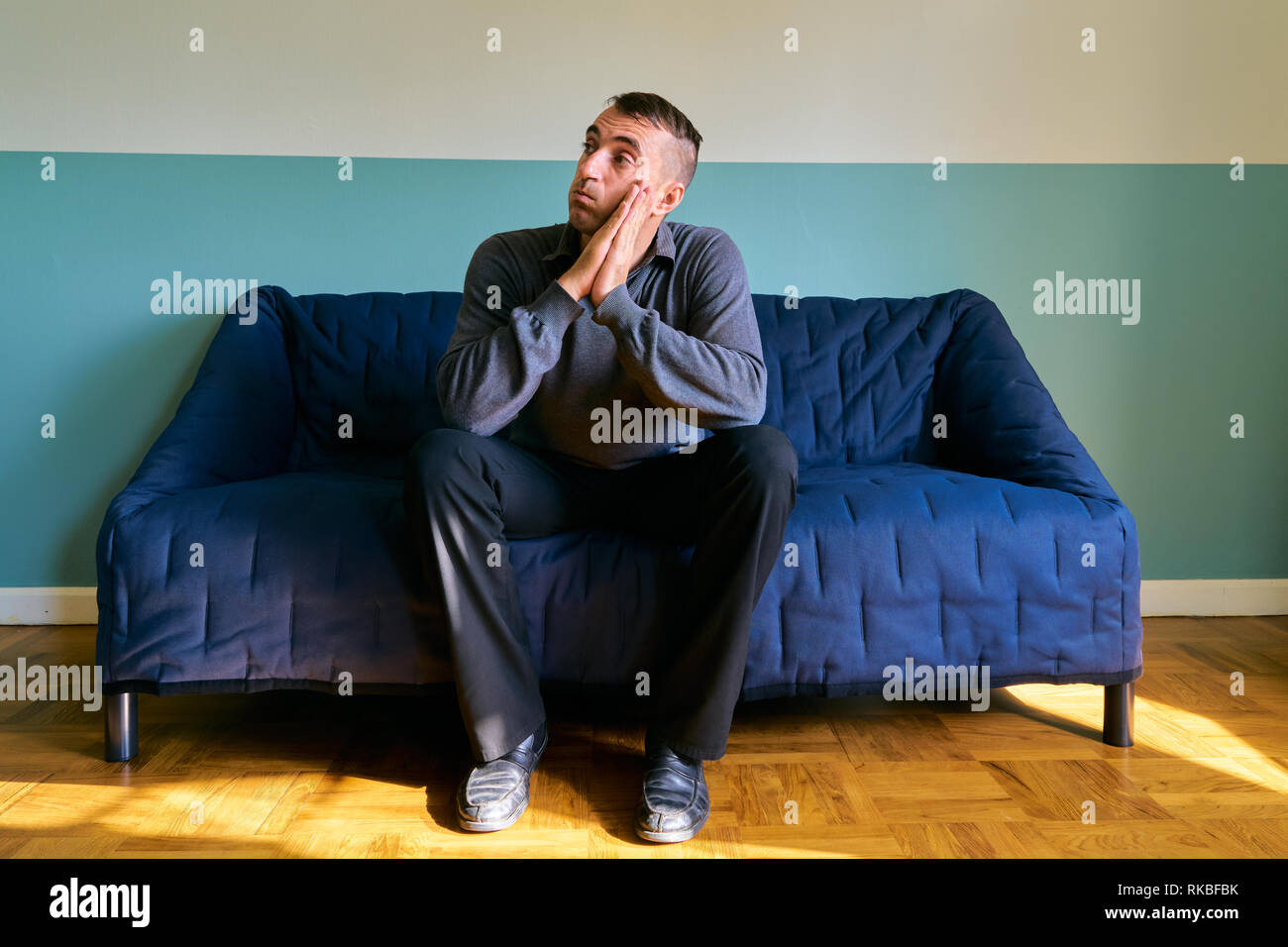 Handsome guy posing - bored caucasian man sitting on sofa and worried ...
