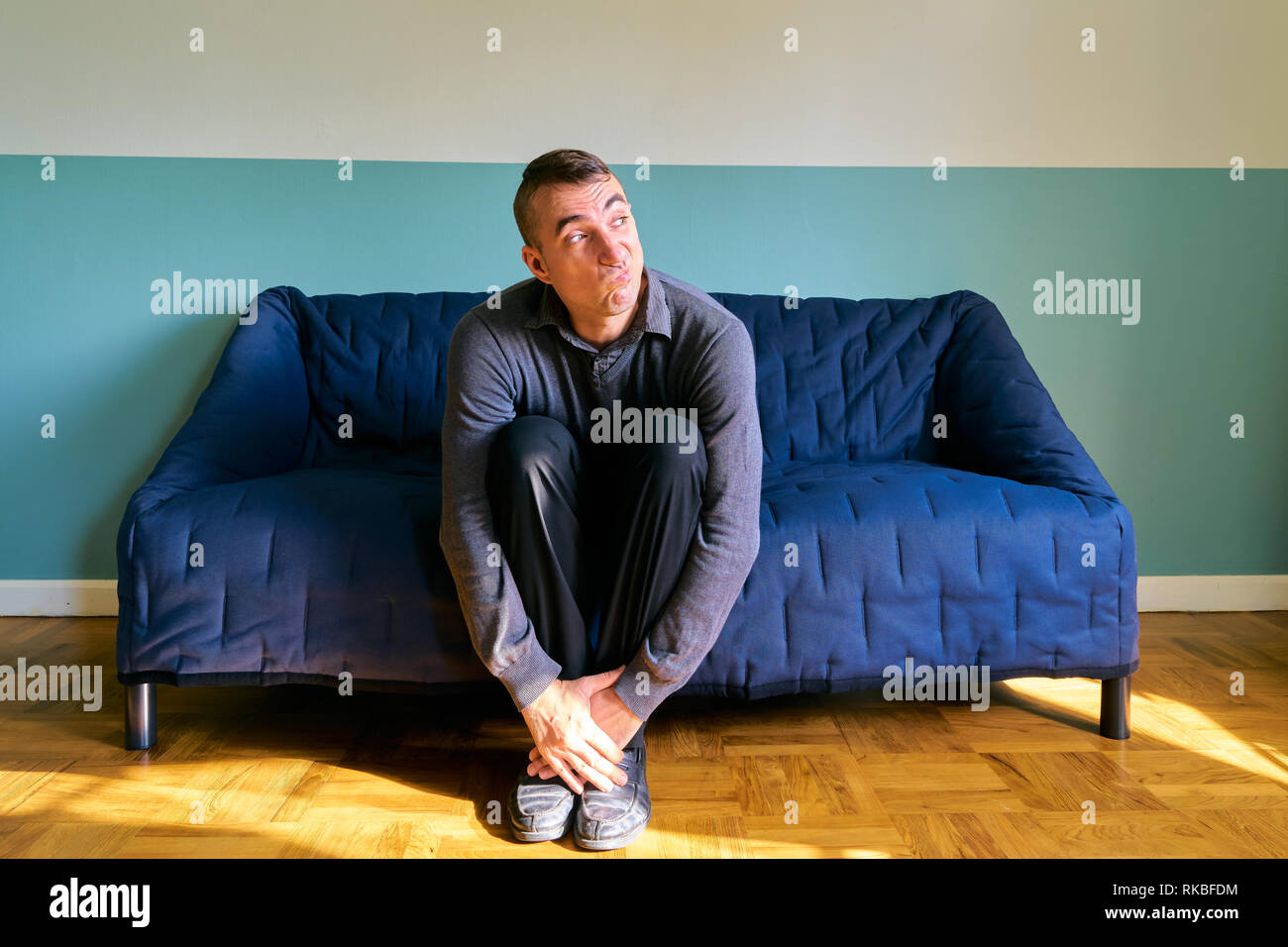Handsome guy posing - bored caucasian man sitting on the sofa and ...