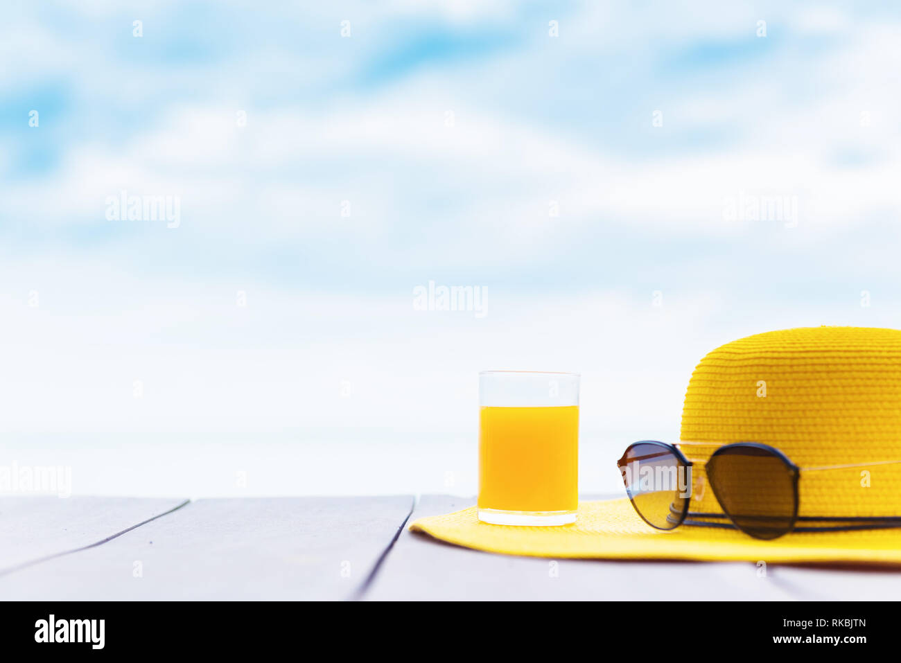 Yellow hat with fresh orange juice on the beach. Summer vacation with ...