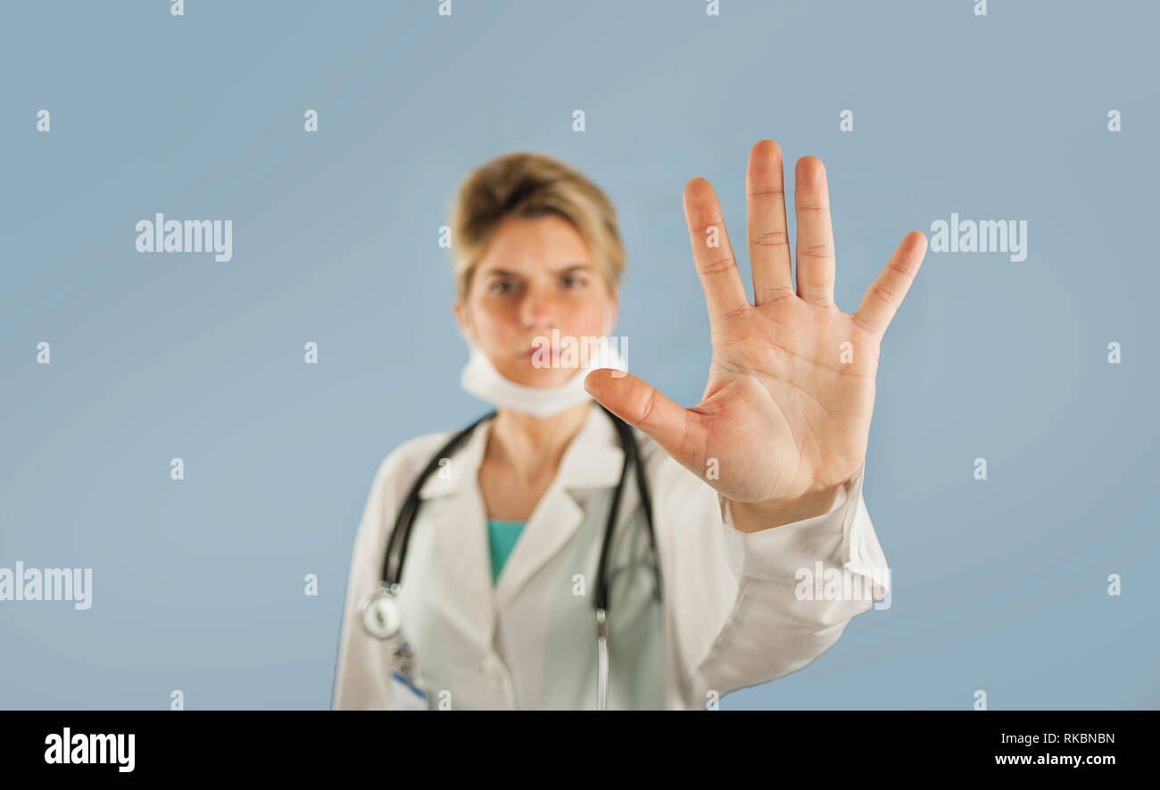 Young girl doctor shows with hand palm stop sign on a blue isolated ...