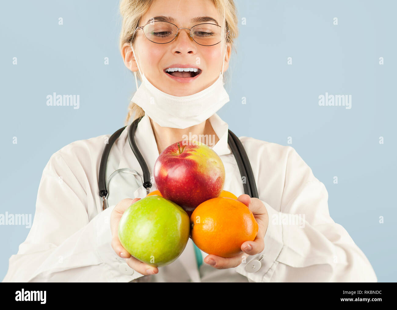 beautiful girl doctor nutritionist with fruit in hand on blue isolated ...