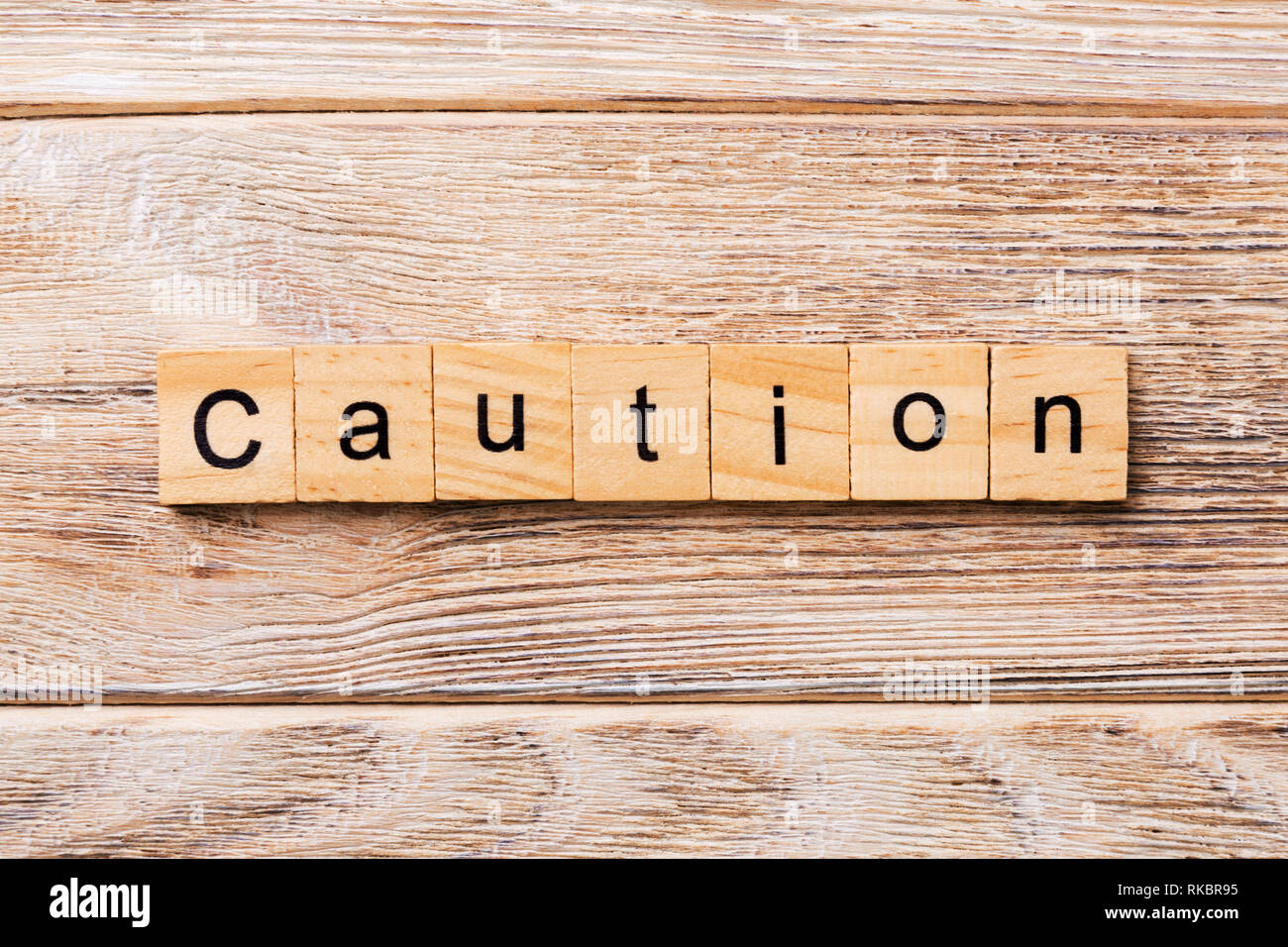 CAUTION word written on wood block. CAUTION text on wooden table for ...