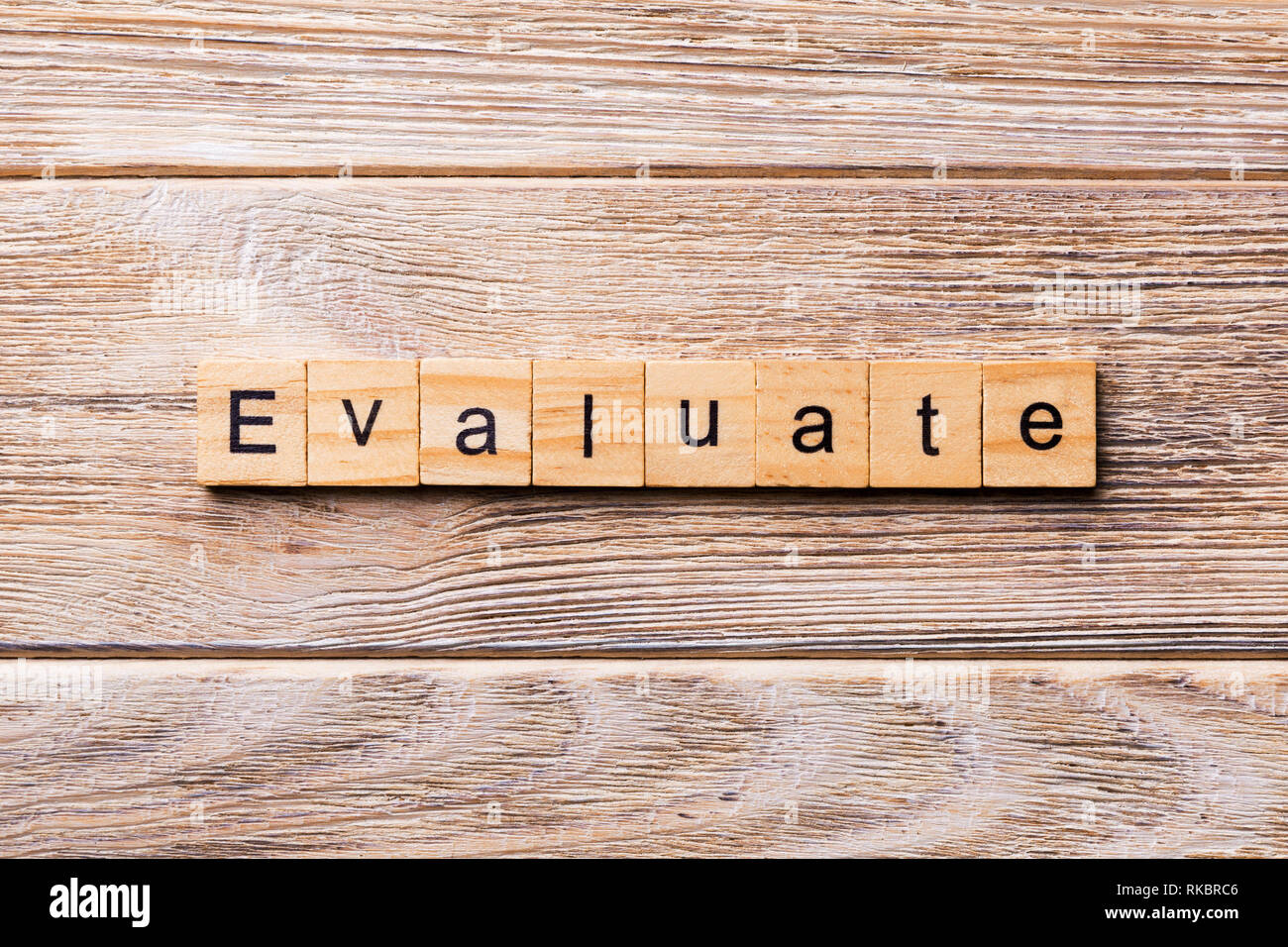 EVALUATE word written on wood block. EVALUATE text on wooden table for ...