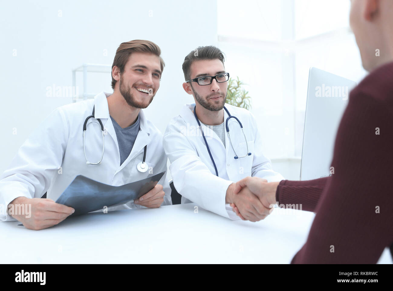 doctor at the clinic giving an handshake to his patient, healthcare and ...