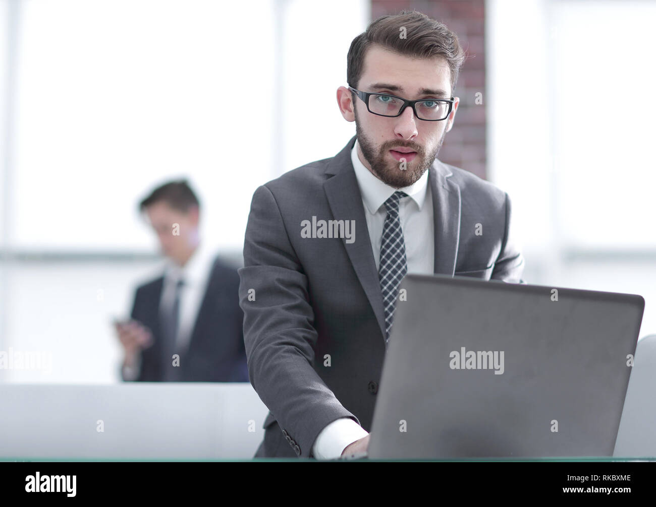 Serious man doing business with a laptop on the office background Stock ...