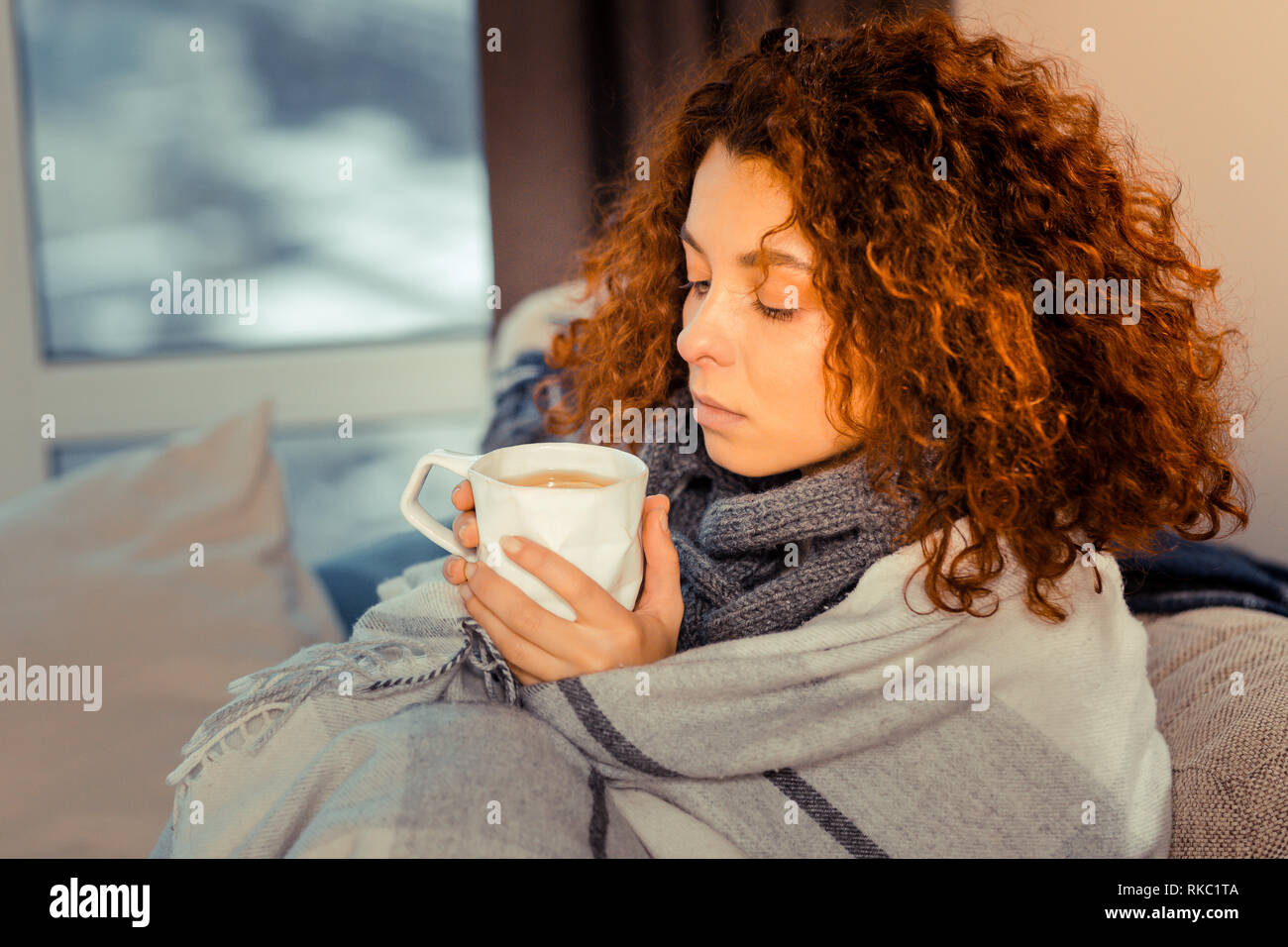 Beautiful curly woman drinking hot tea while feeling sick Stock Photo ...
