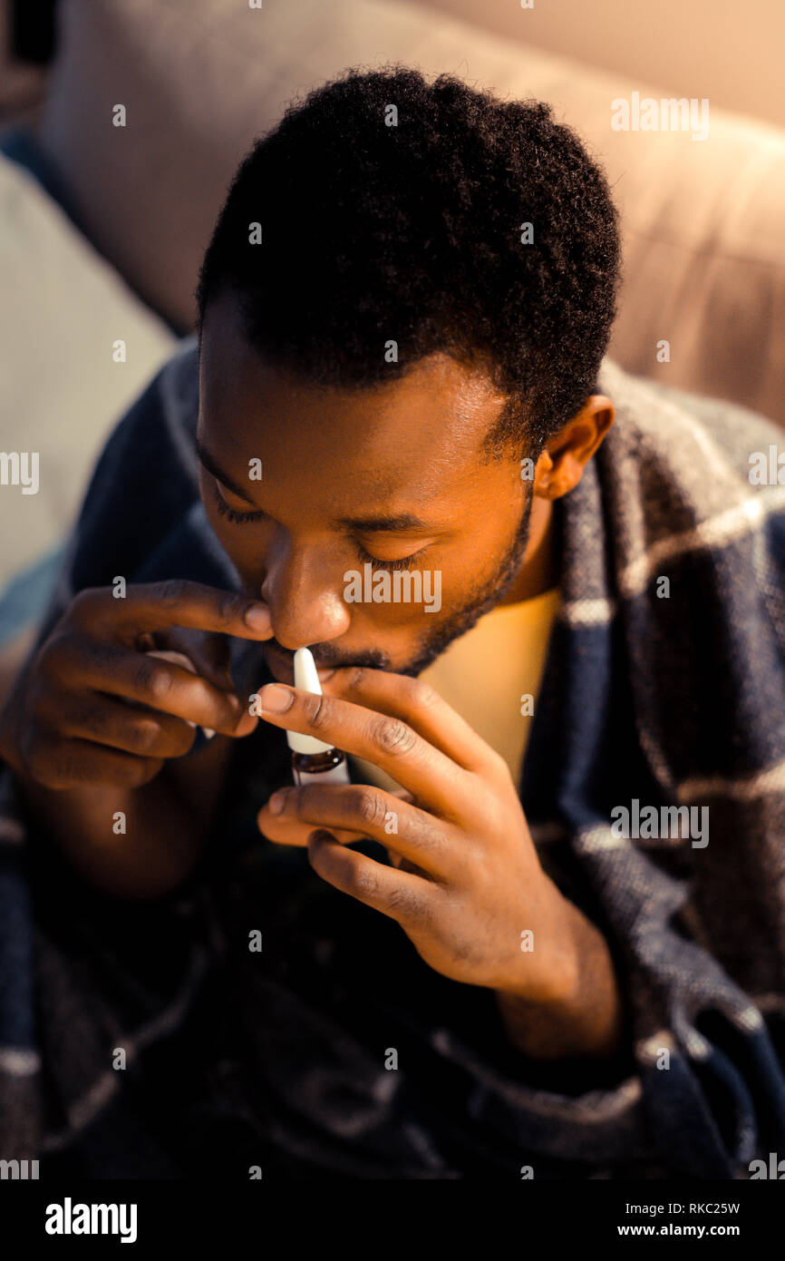 Bearded man with plaid on his shoulders using nose spray Stock Photo ...