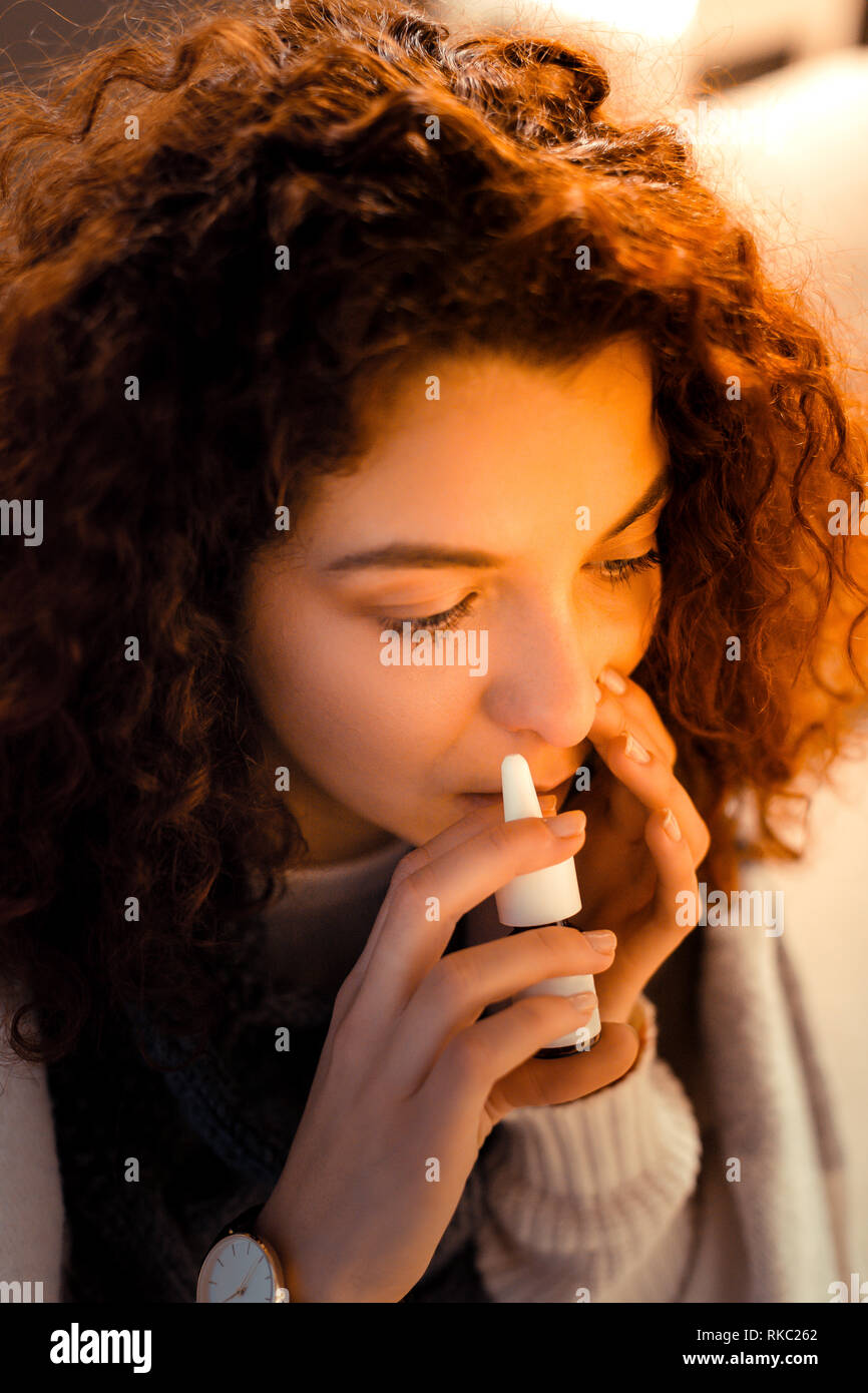 Close up of young red-haired woman using nose spray at home Stock Photo ...