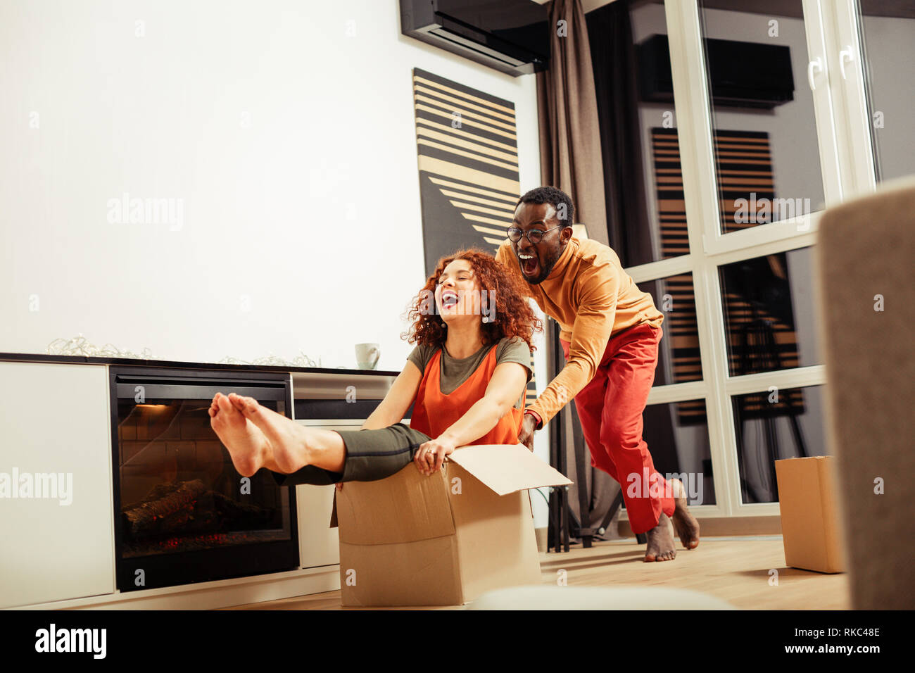 Laughing African-American husband directing box with his wife Stock ...