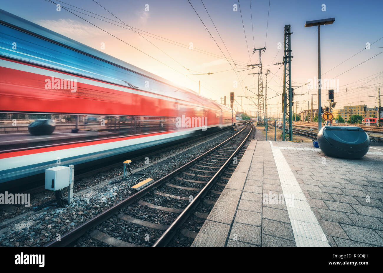 Red high speed train in motion on the railway station at colorful ...