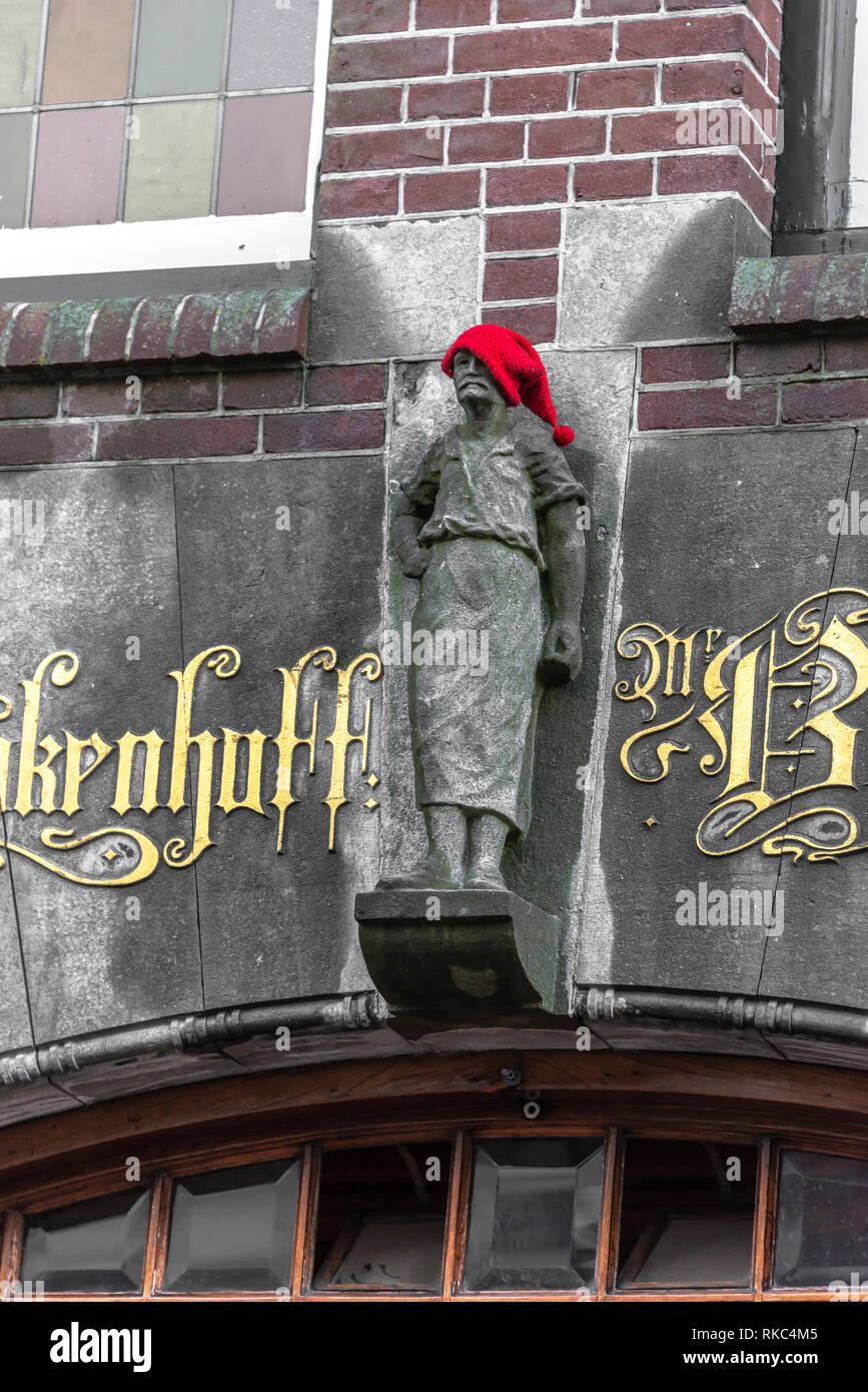 statue of a man with a red cap on his head standing on a stone plinth ...