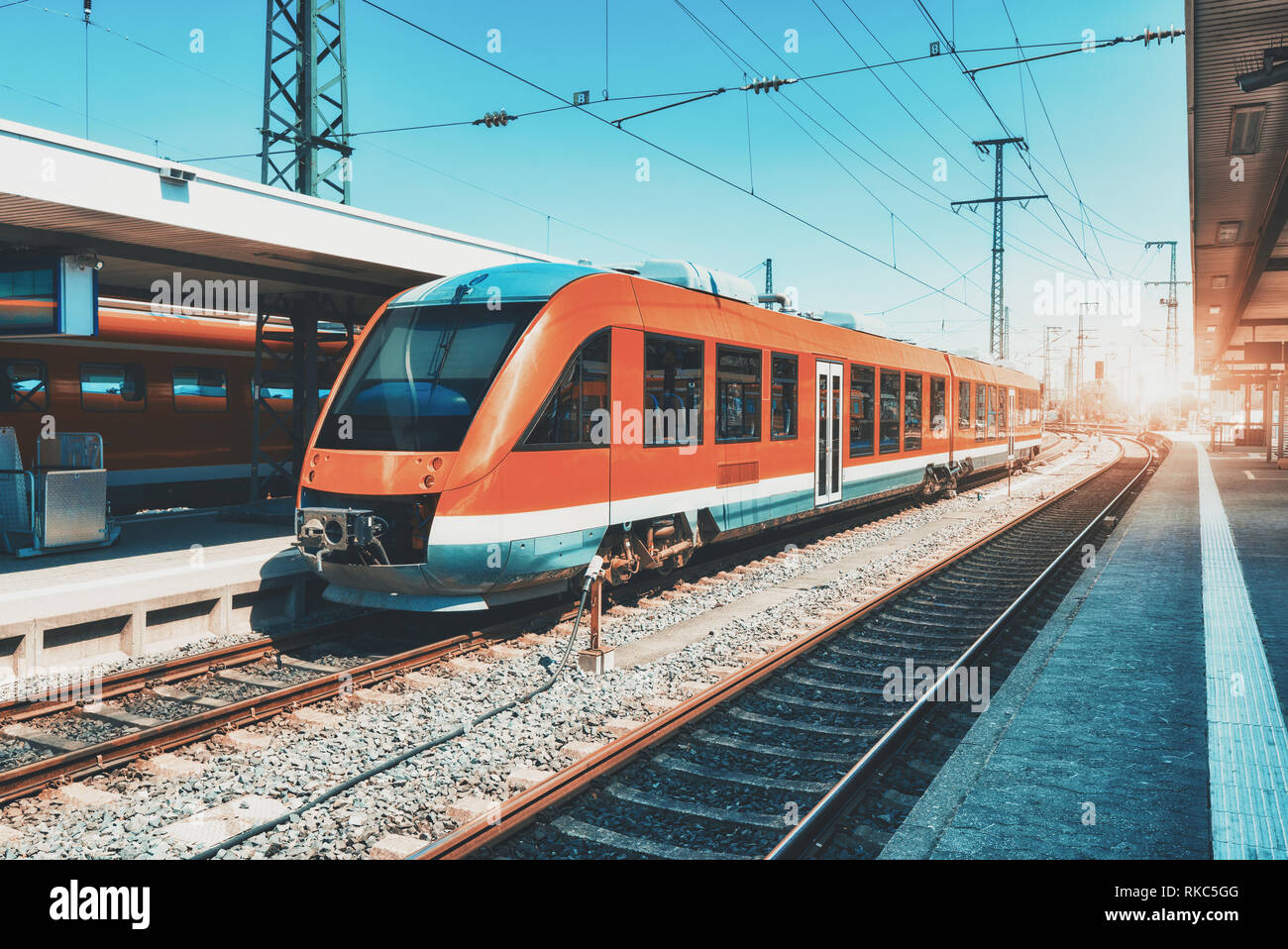 High speed orange train on the railway station at sunset in summer ...
