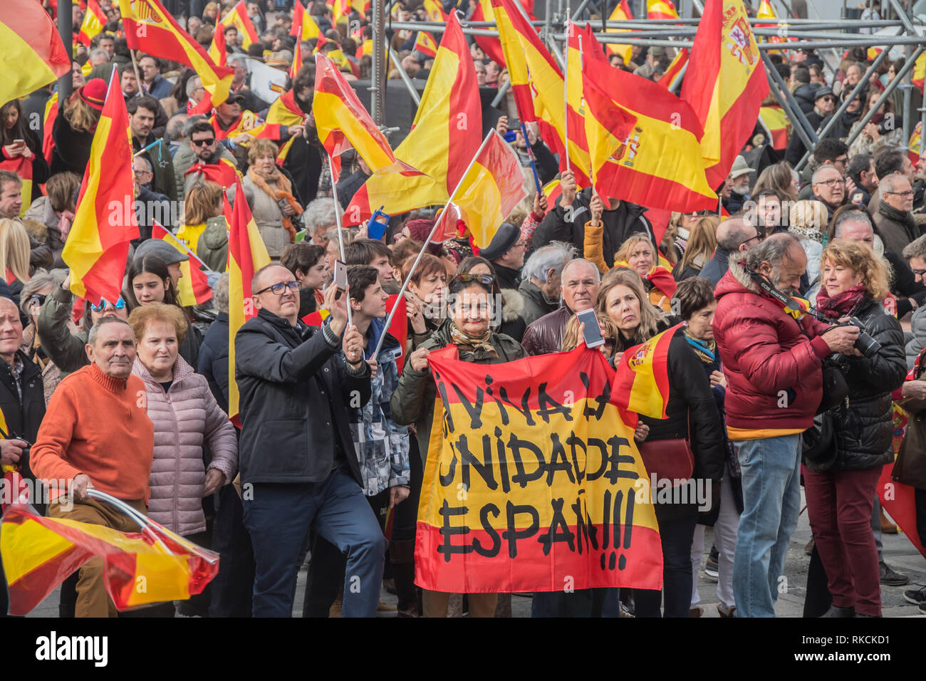 Protesters are seen waving spanish flags and a woman holding a banner ...