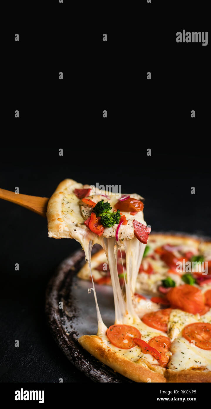 Delicious cheese stringy slice lifted of full supreme pizza baked fresh ...